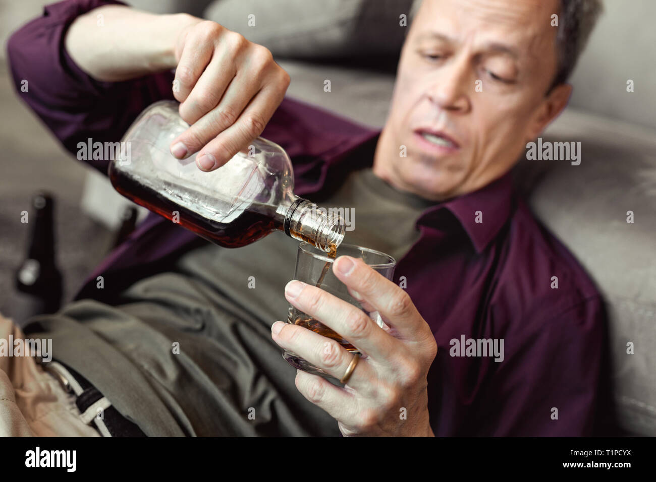 Helpless adult man adding more alcohol into his glass Stock Photo - Alamy