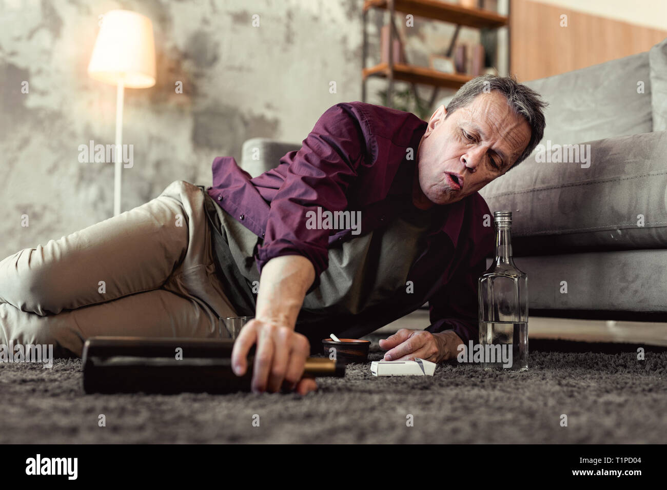 Successful old man taking empty bottle of wine on carpet Stock Photo ...