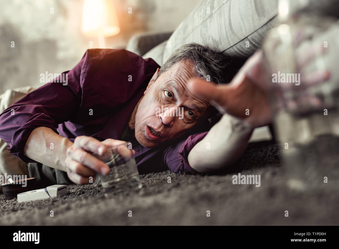 Disgusting drunk man grabbing bottle of vodka while lying Stock Photo ...