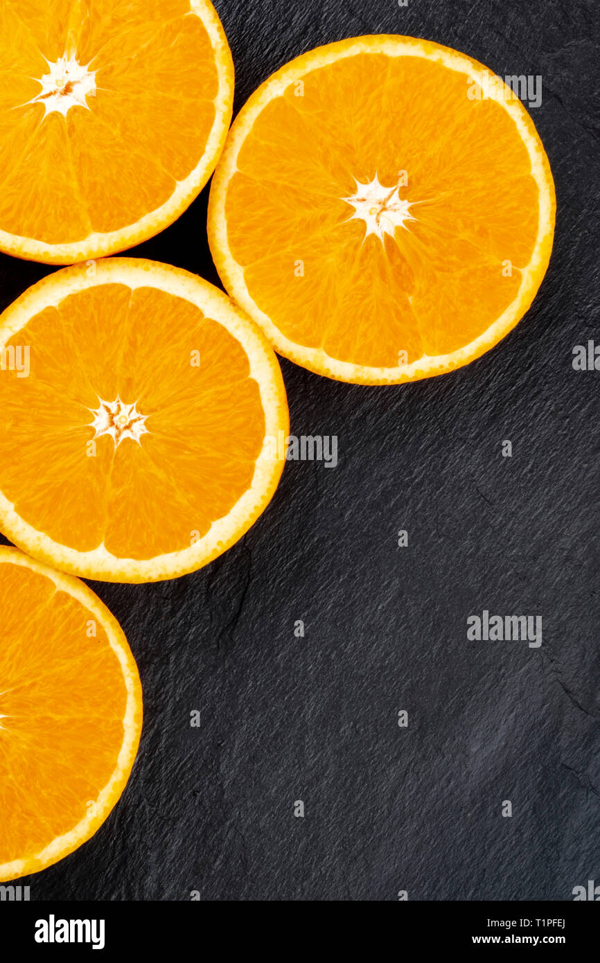 A closeup photo of orange halves, shot from the top on a black ...