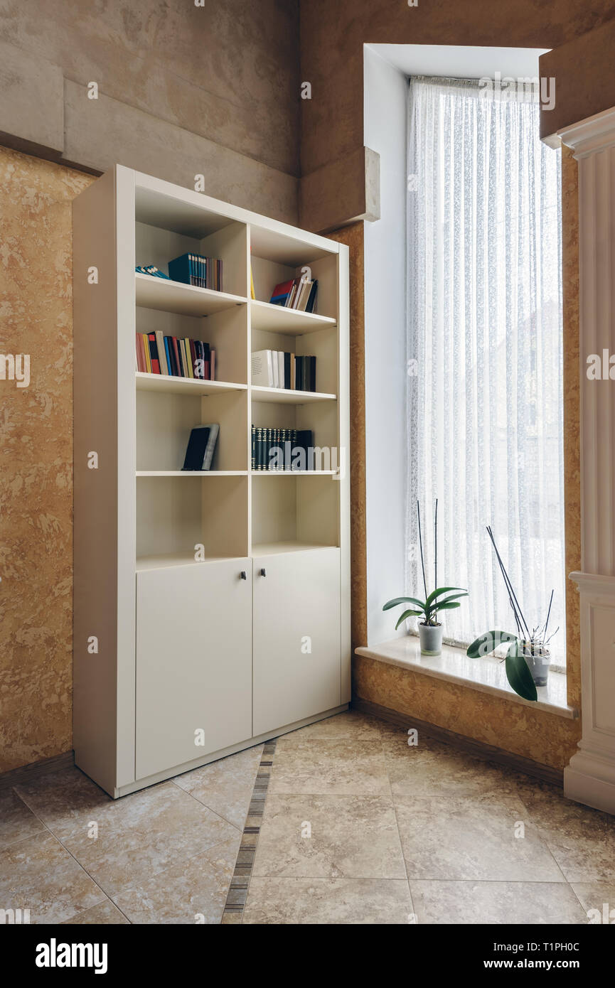 bookcase near window in the big hall Stock Photo - Alamy