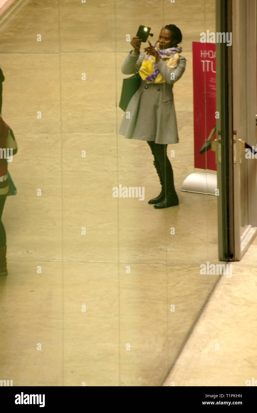 London, UK - April 01, 2015: A young black woman is taking mobile phone ...
