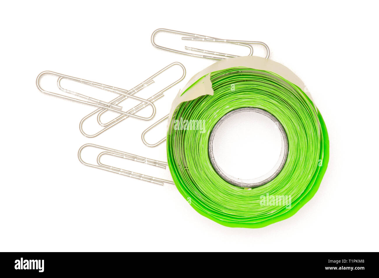 Five paper clips with a green sticker roll flatlay isolated on white ...