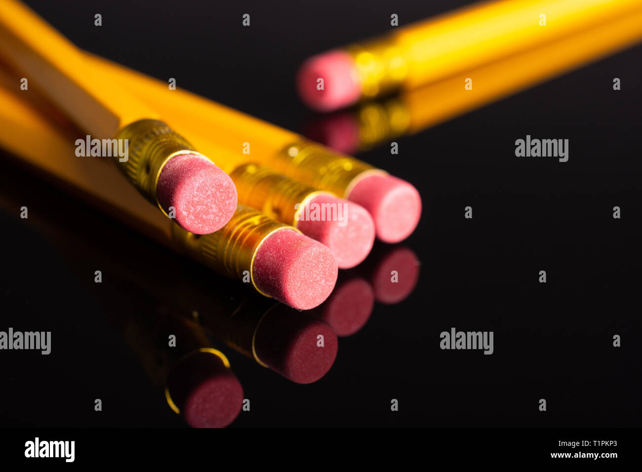 Group of five whole yellow pencil cup eraser isolated on black glass ...