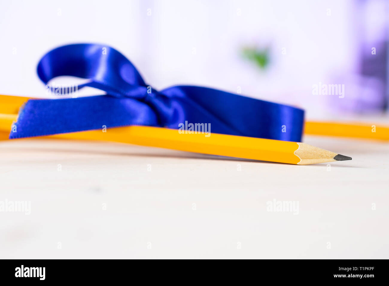 Group of two whole yellow pencil tied by ribbon with red flowers on ...