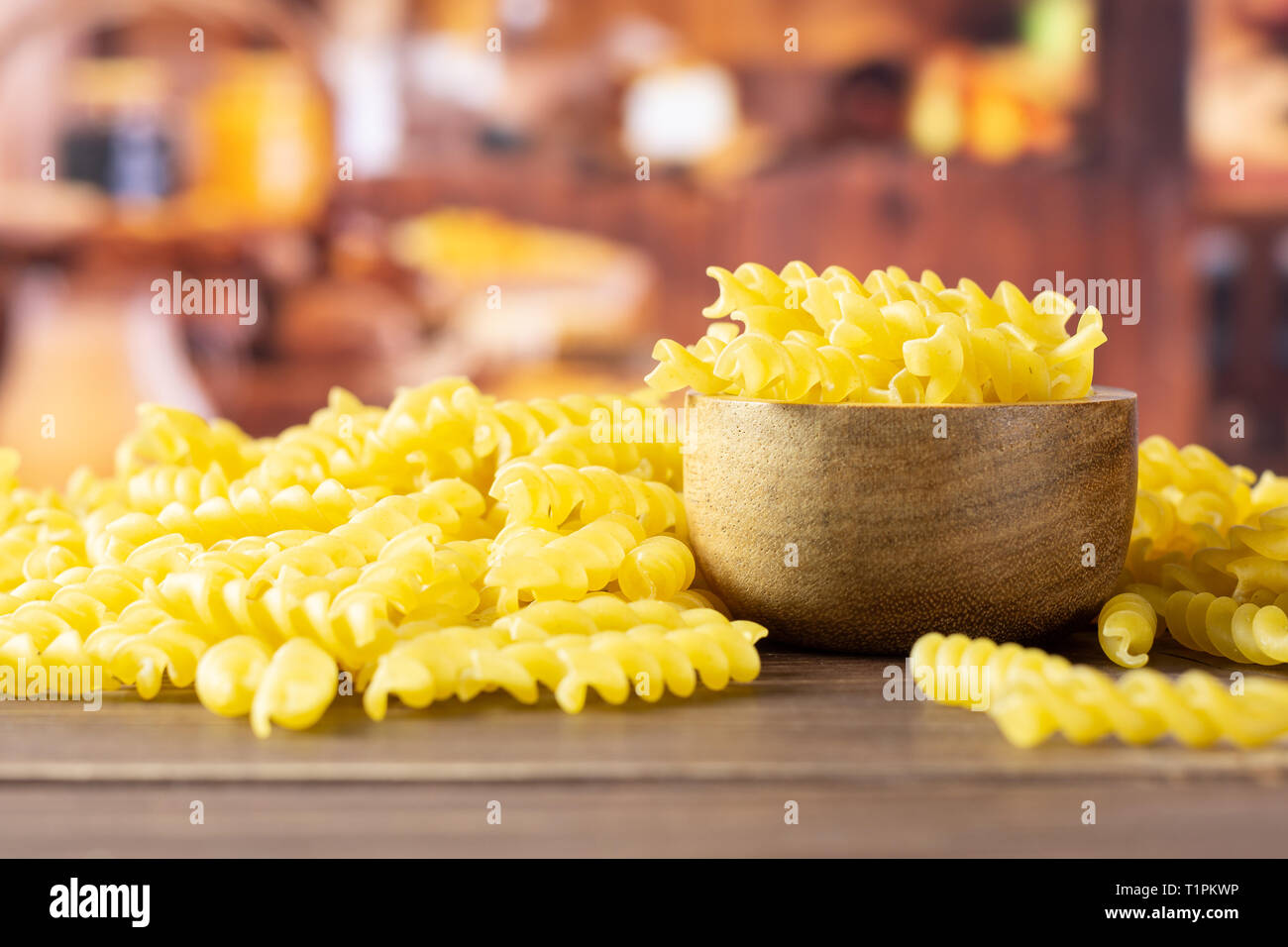Lot of pieces of raw italitan yellow pasta torti with wooden bowl with ...