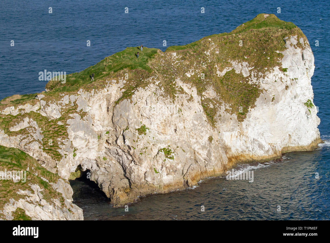 People walking along a limestone headland in County Antrim, Northern ...