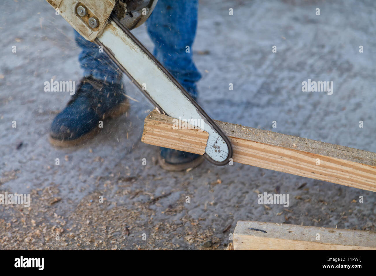 A man using a chainsaw saws a wooden beam Stock Photo - Alamy