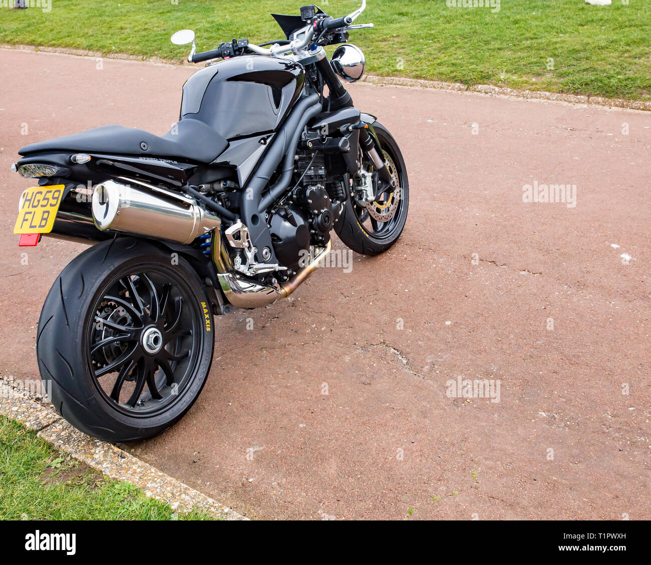 A side on view of a black Triumph Speed Triple motorcycle parked up on ...
