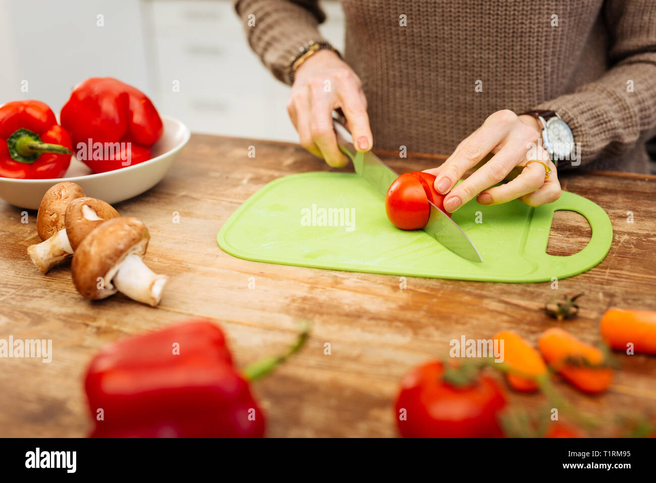 Neat woman in warm sweater getting her dinner ready while chopping ...