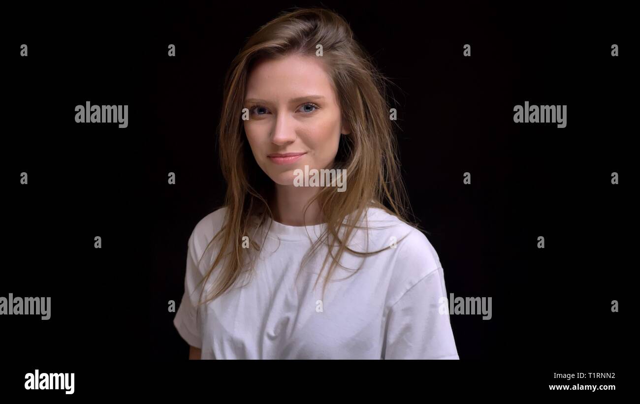 Portrait of young caucasian long-haired girl in shirt smiling shyly ...