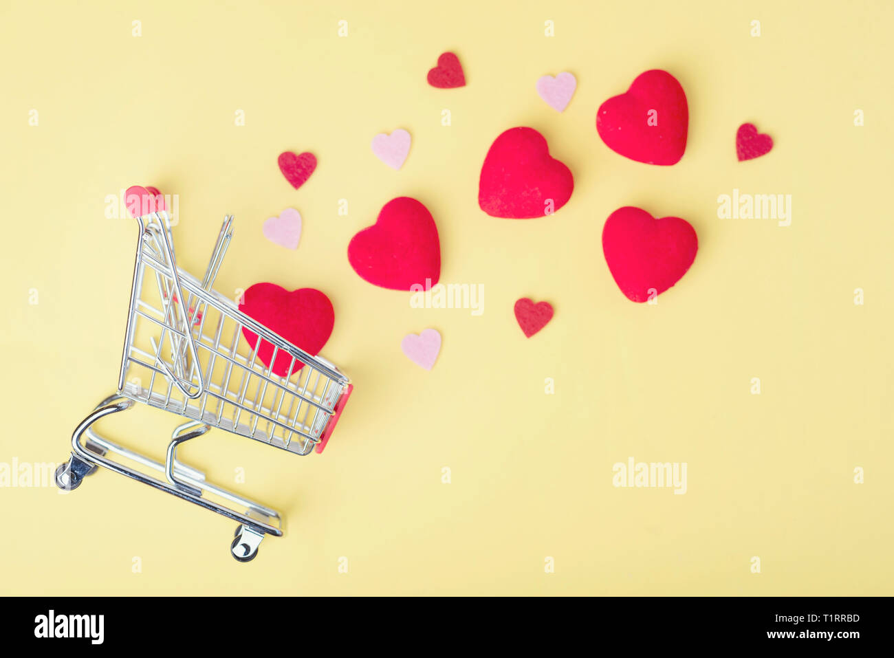 hearts with shopping cart on yellow background Stock Photo - Alamy