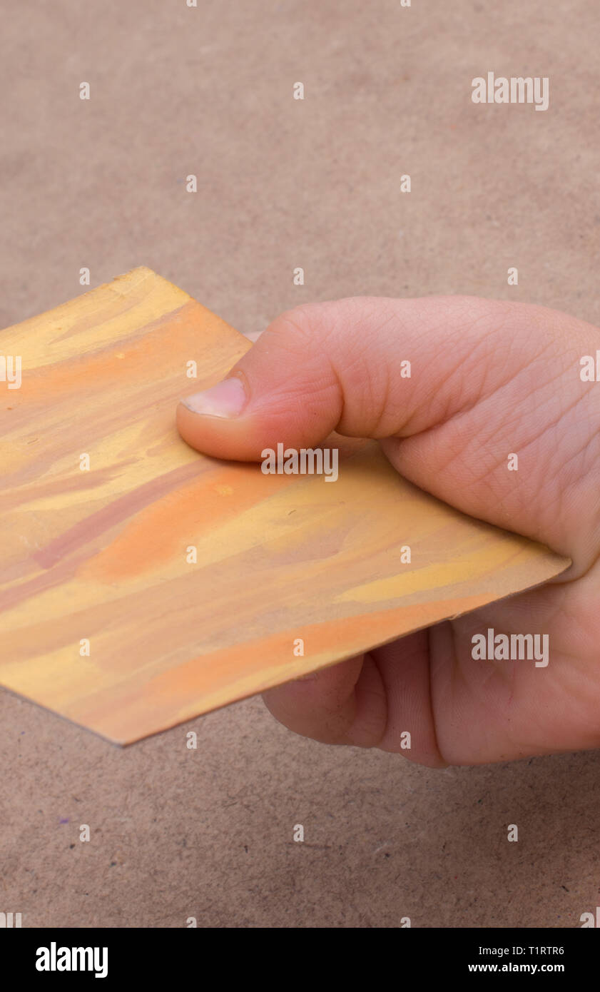 Hand holding painted note paper on brown background Stock Photo - Alamy