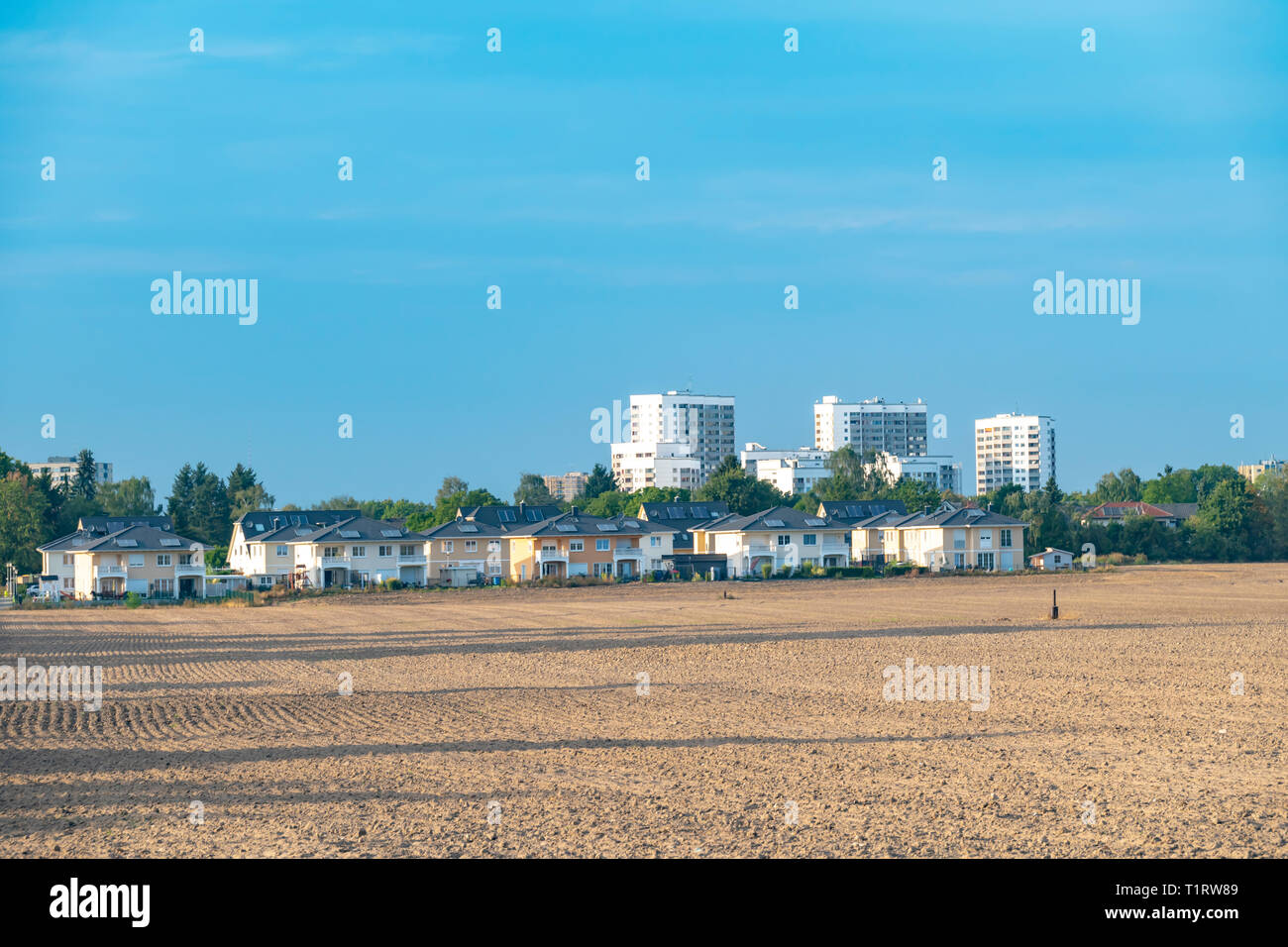 View over a harvested field and small houses to the satellite city ...