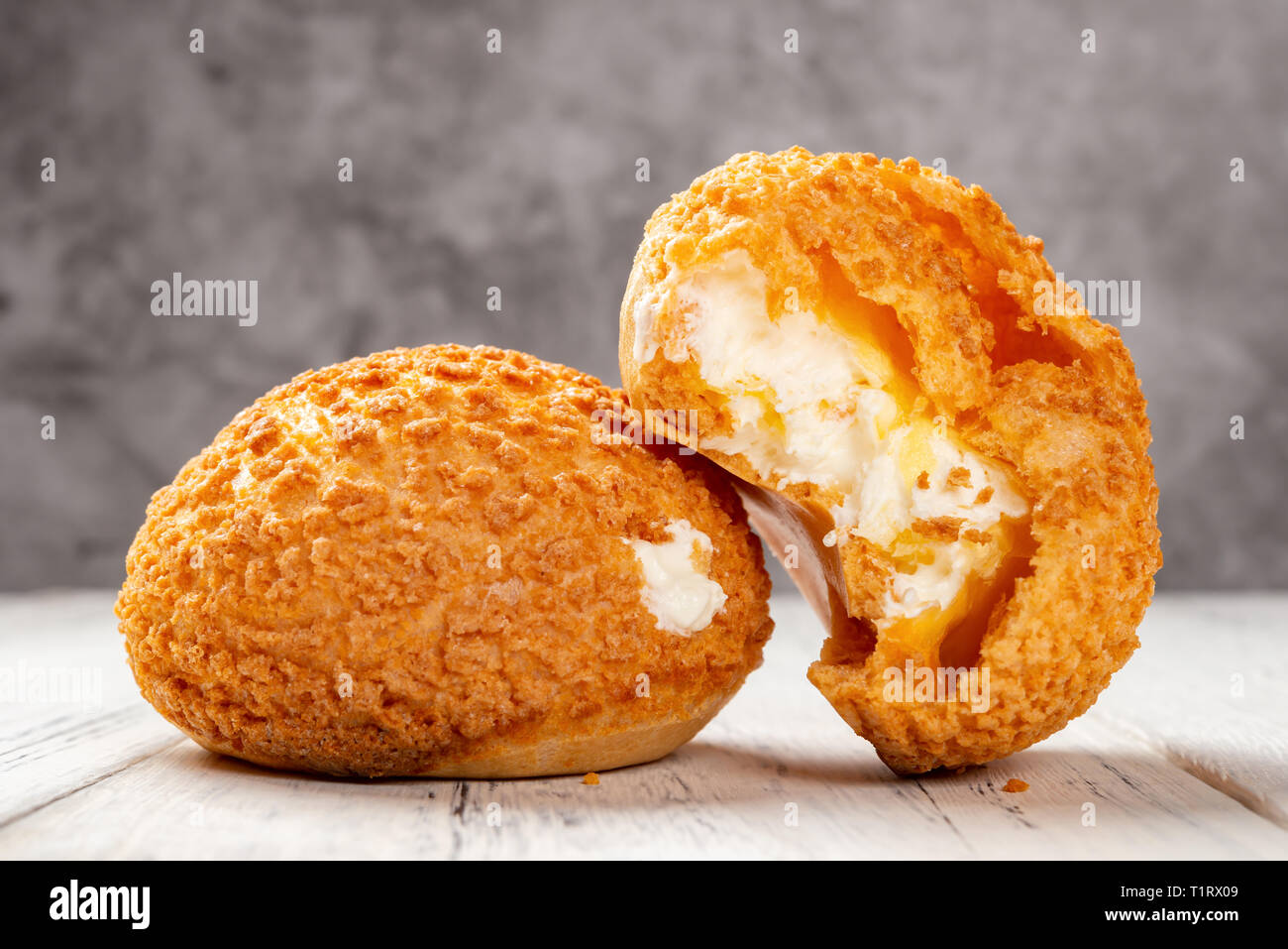 two pieces sweet puffs and one with a bite on a white wood table Stock ...