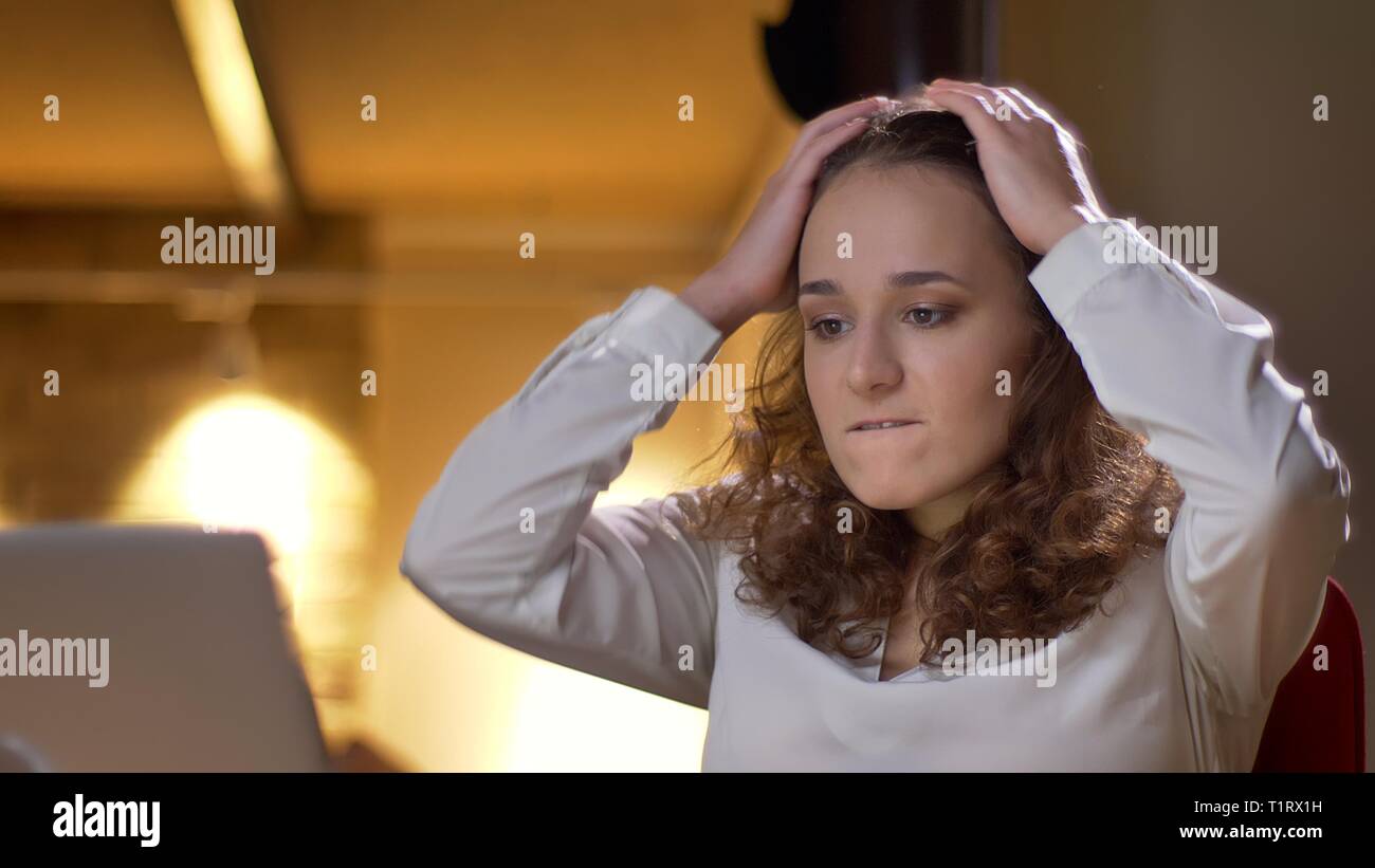 Portrait of concentrated young businesswoman watching into laptop with ...