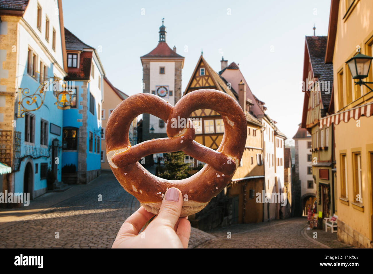 The girl holds in her hand a traditional German pretzel on the ...
