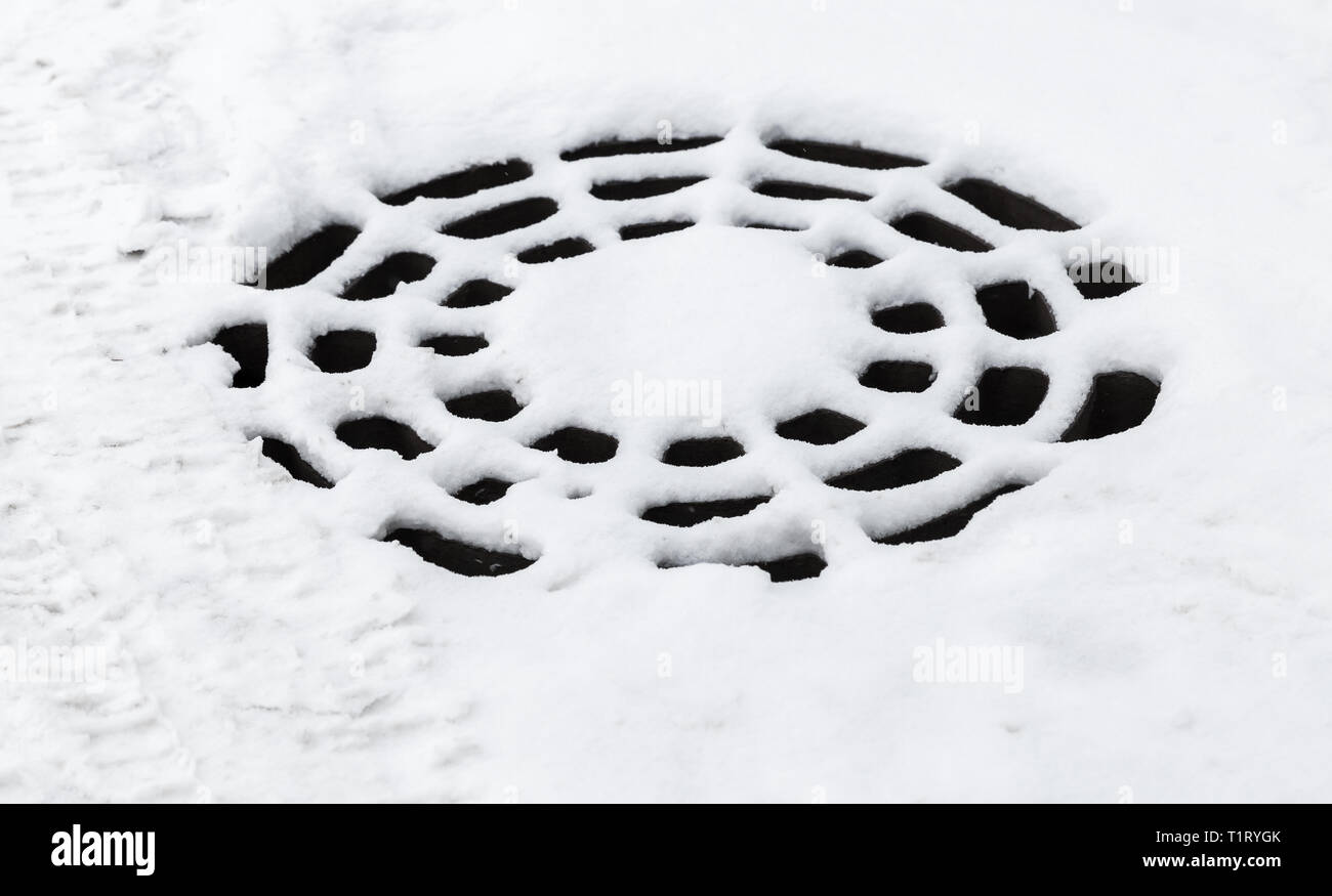 Round sewer manhole covered with snow Stock Photo - Alamy