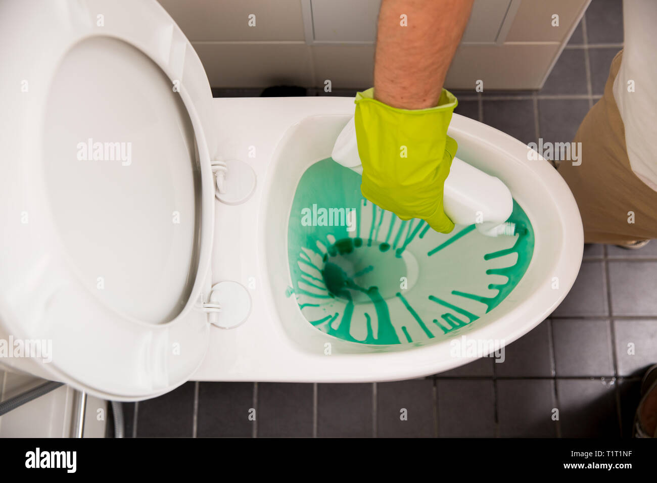 Man in rubber protective gloves cleaning, washing toilet with brush and ...