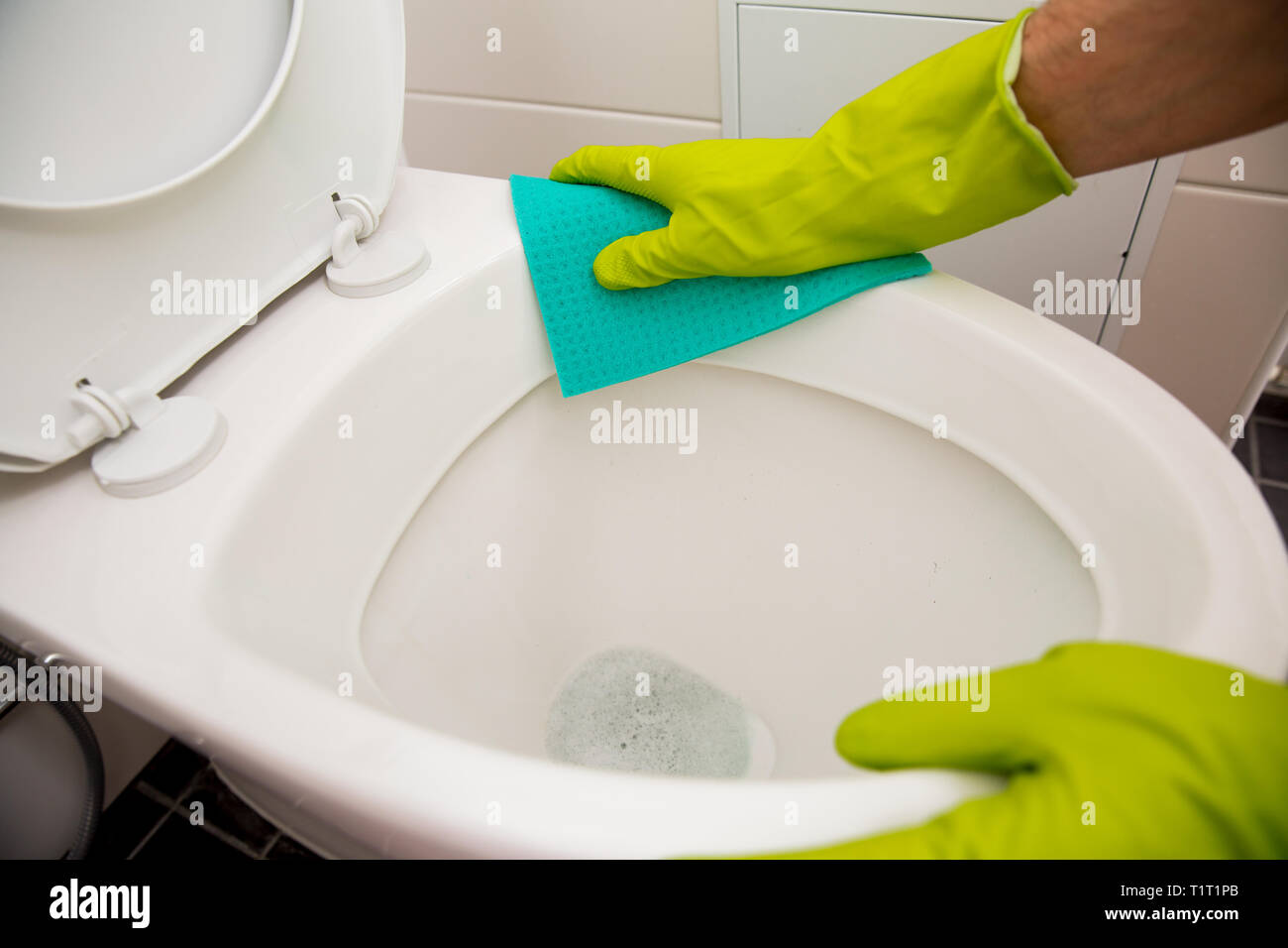 Man in rubber protective gloves cleaning, washing toilet with brush and ...
