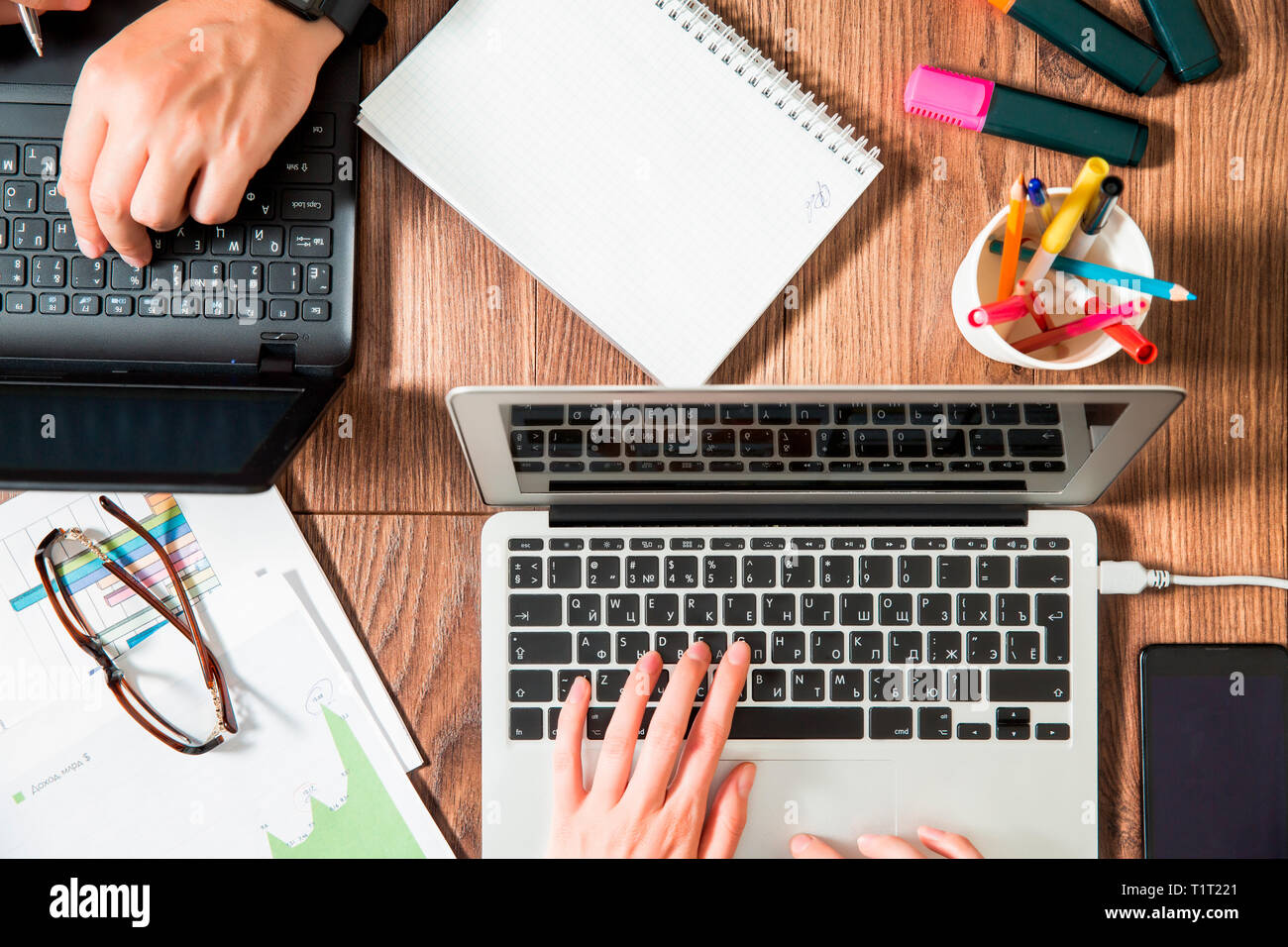 Two business persons working at office desk, typing and using laptop ...