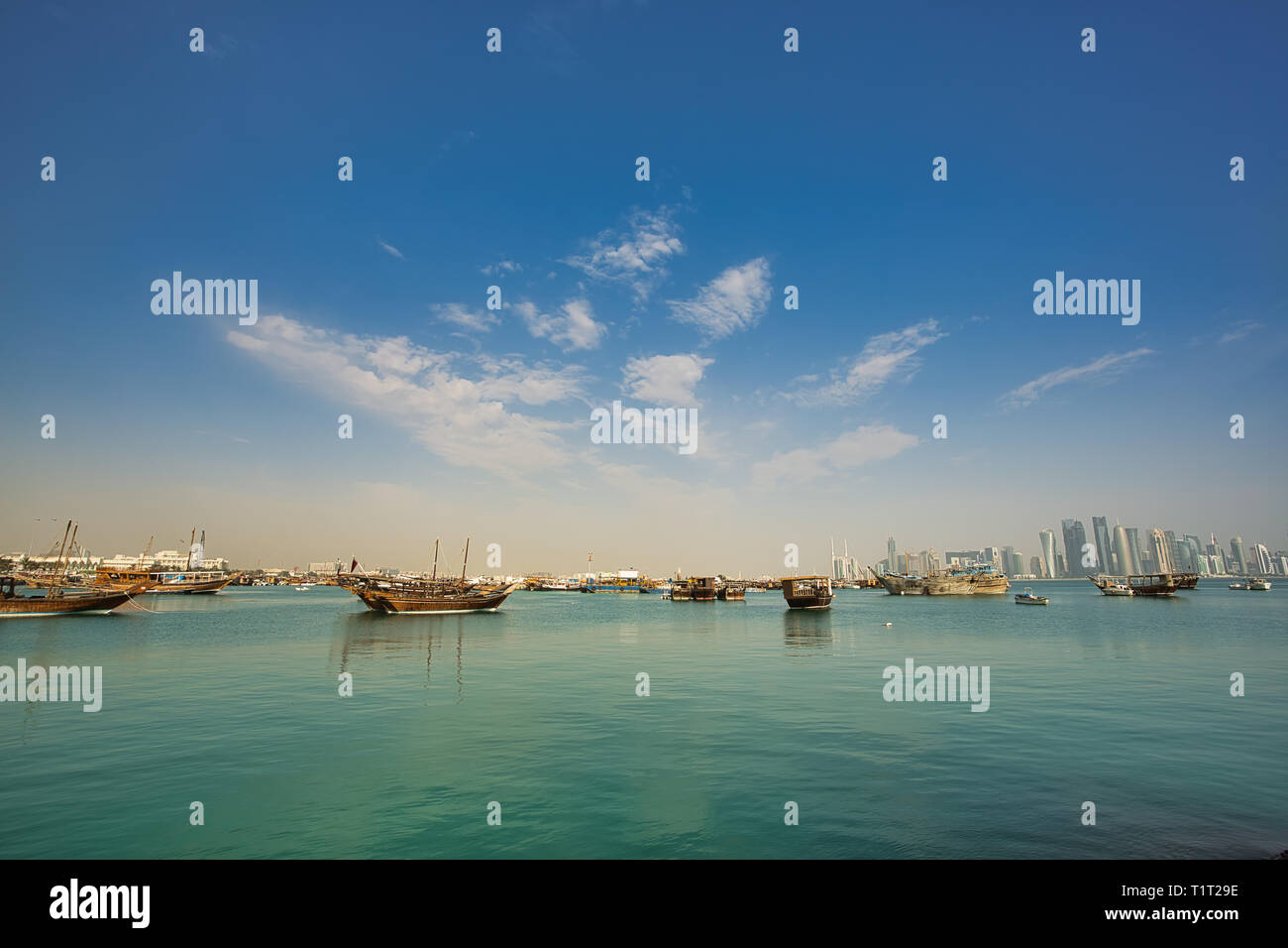 The wooden dhow boats in Doha harbor and numerous skyscrapers, covered ...