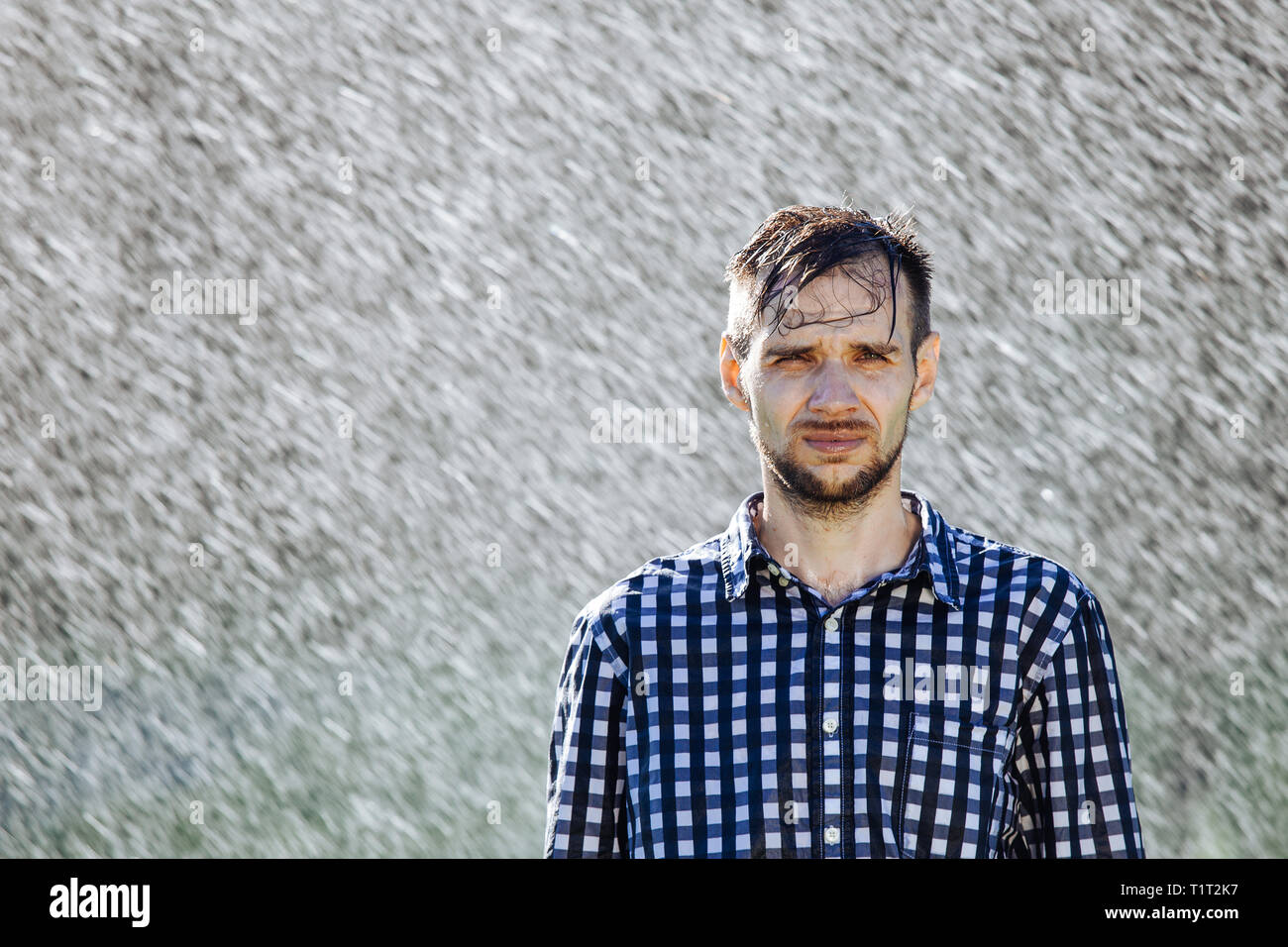 The farmer in the hat is enjoying the rain. Young man getting wet under ...