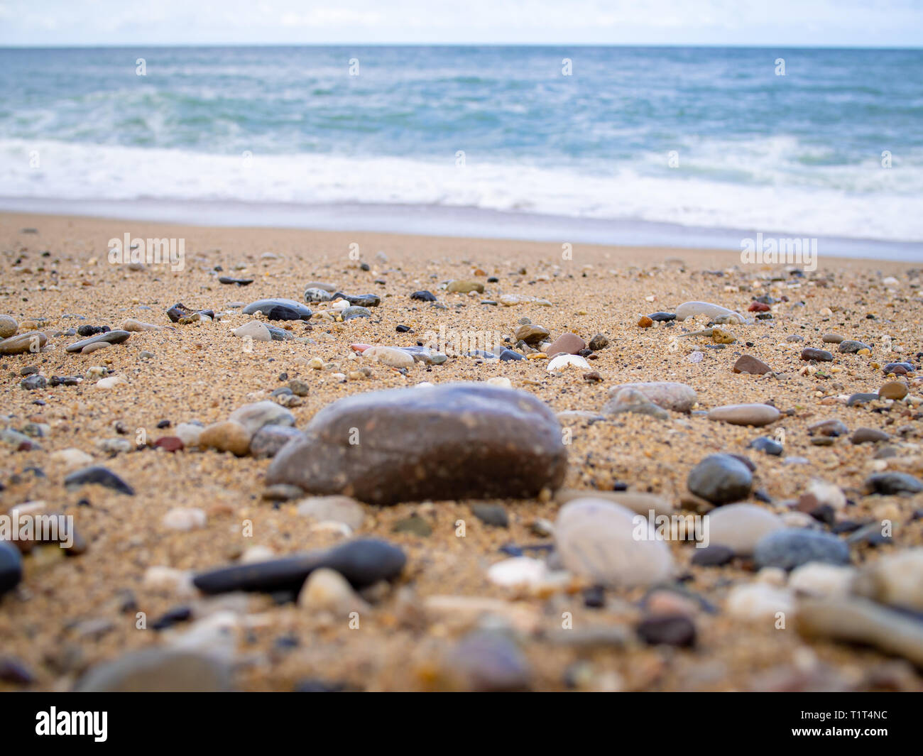 Pebbles on the beach close up on the sea surf background, copy space ...