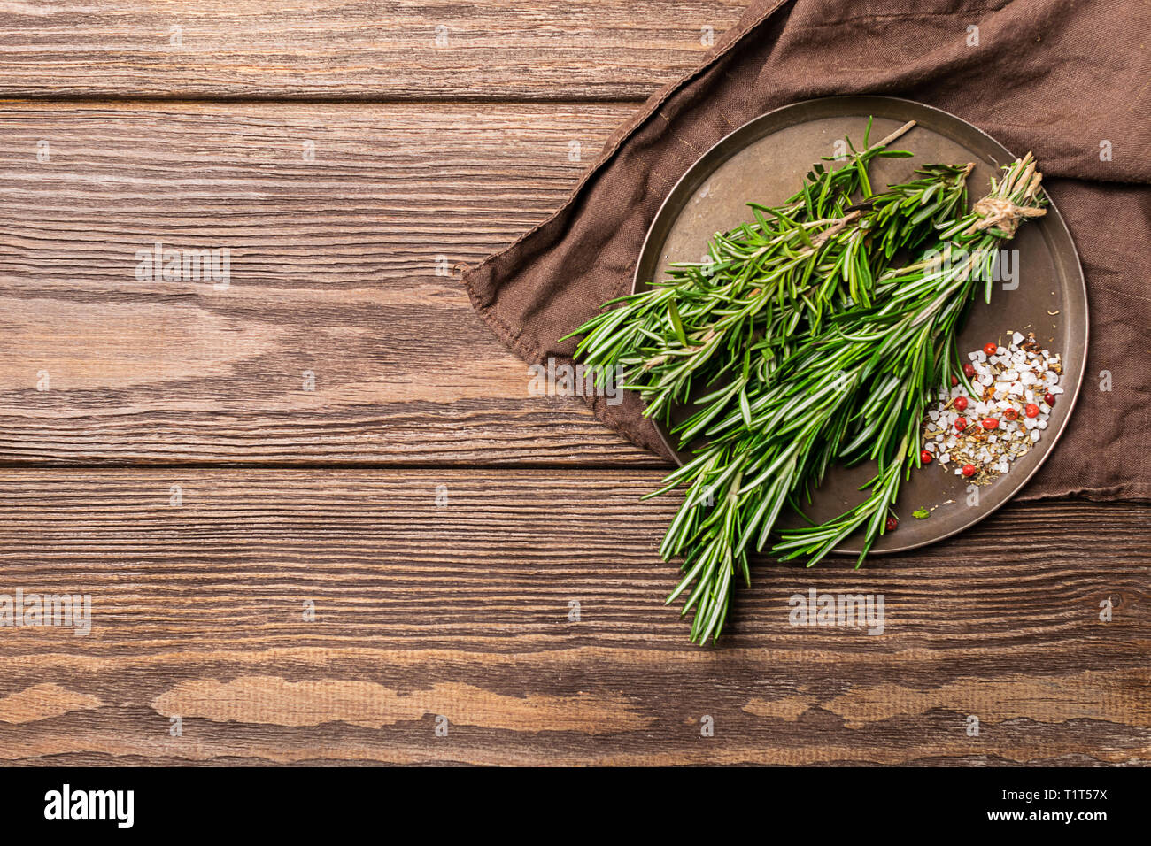 Seasoning a bunch of fresh fragrant rosemary, salt, red peas on a brown ...