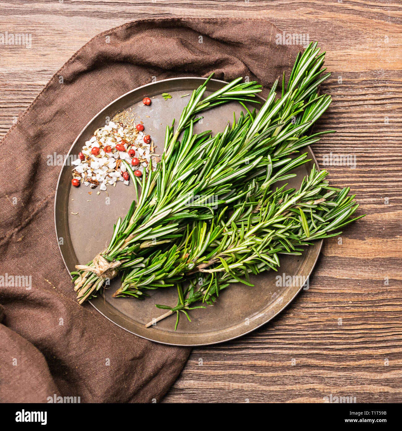 Seasoning a bunch of fresh fragrant rosemary on a brown wooden ...
