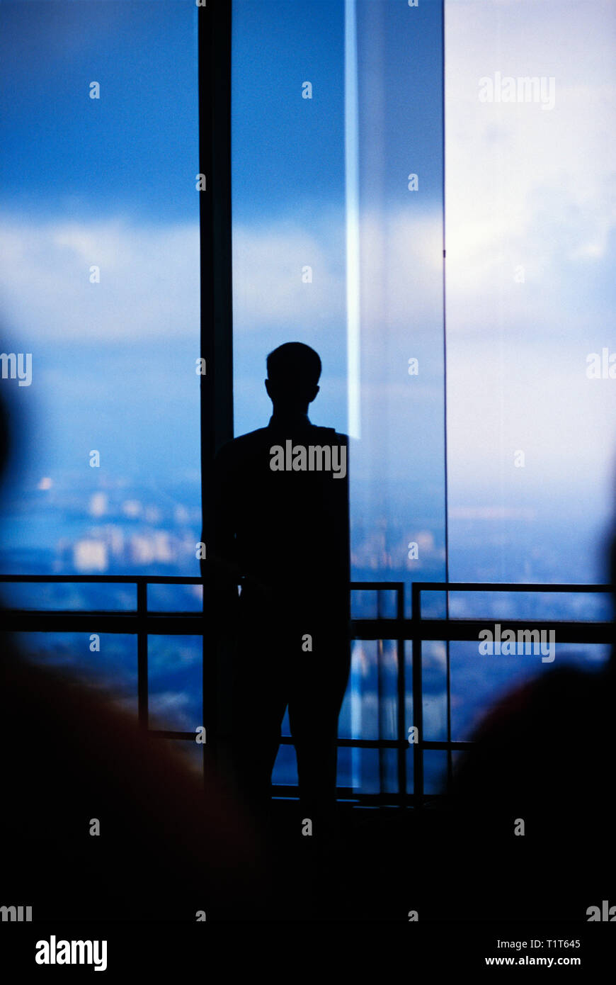 Man looking out of office window in very tall building Stock Photo - Alamy