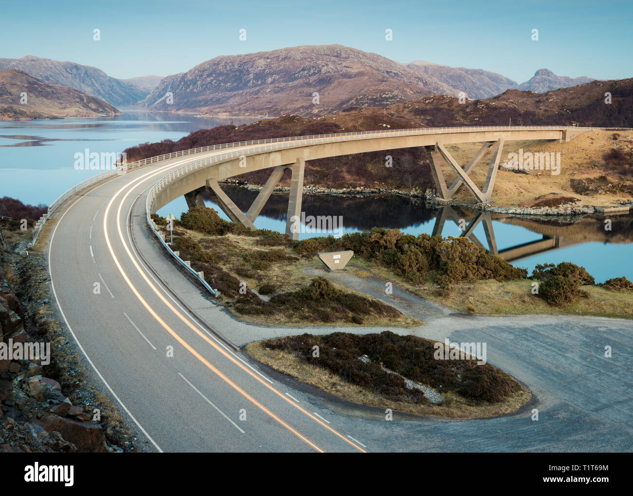 The Kylesku Bridge crossing at sunset with car tail light streaks along ...