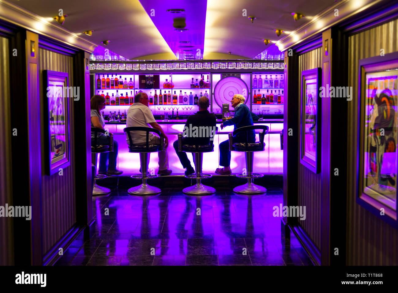 Adults sitting and drinking beer, wine, and alcohol at a colorful bar ...