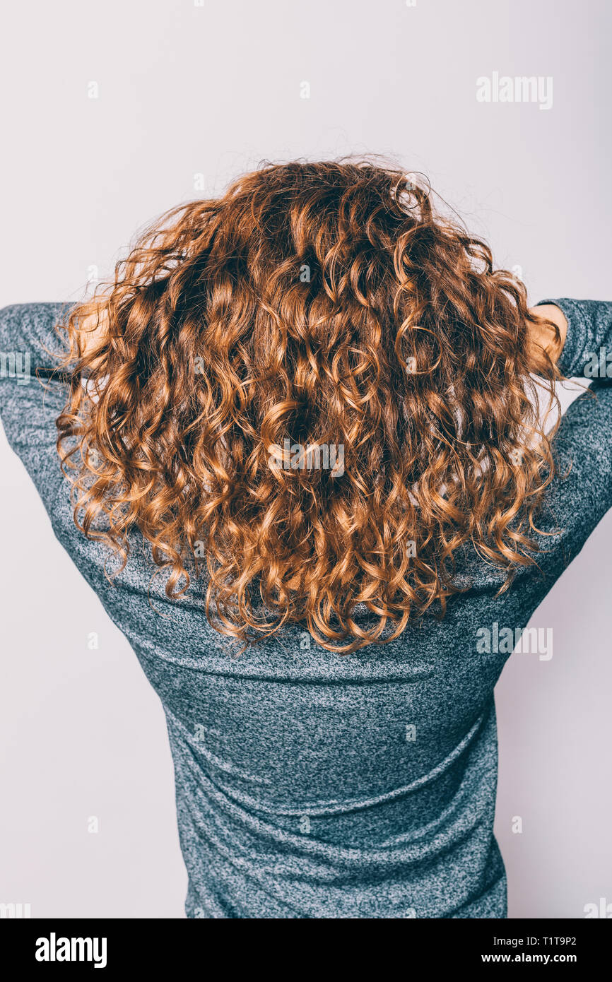 Woman's head with curly brown hair, back view. Close-up unrecognizable ...