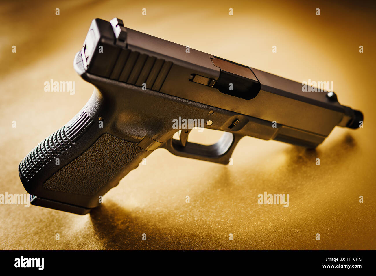 one black handgun on a shiny gold background Stock Photo - Alamy