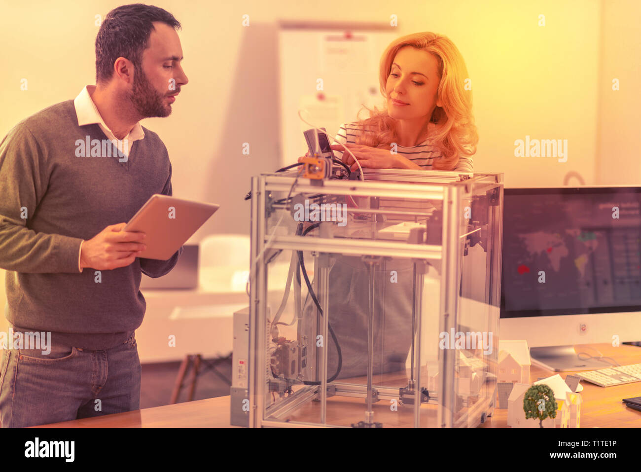 Two earnest coworkers combining their knowledge to get the 3D printer ...