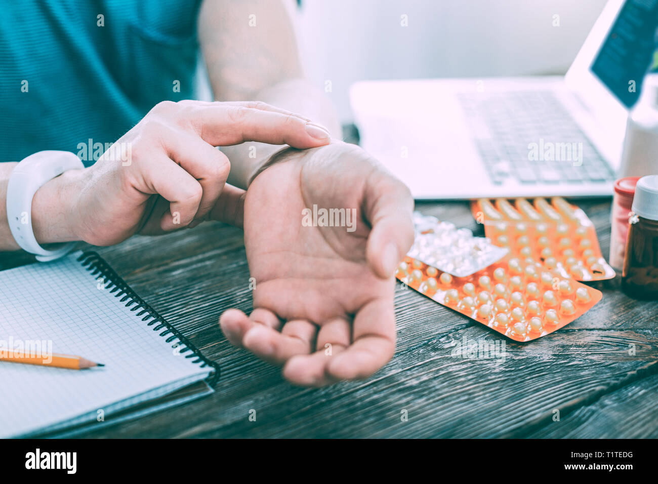 Responsible sick man measuring the pulse in a room Stock Photo - Alamy