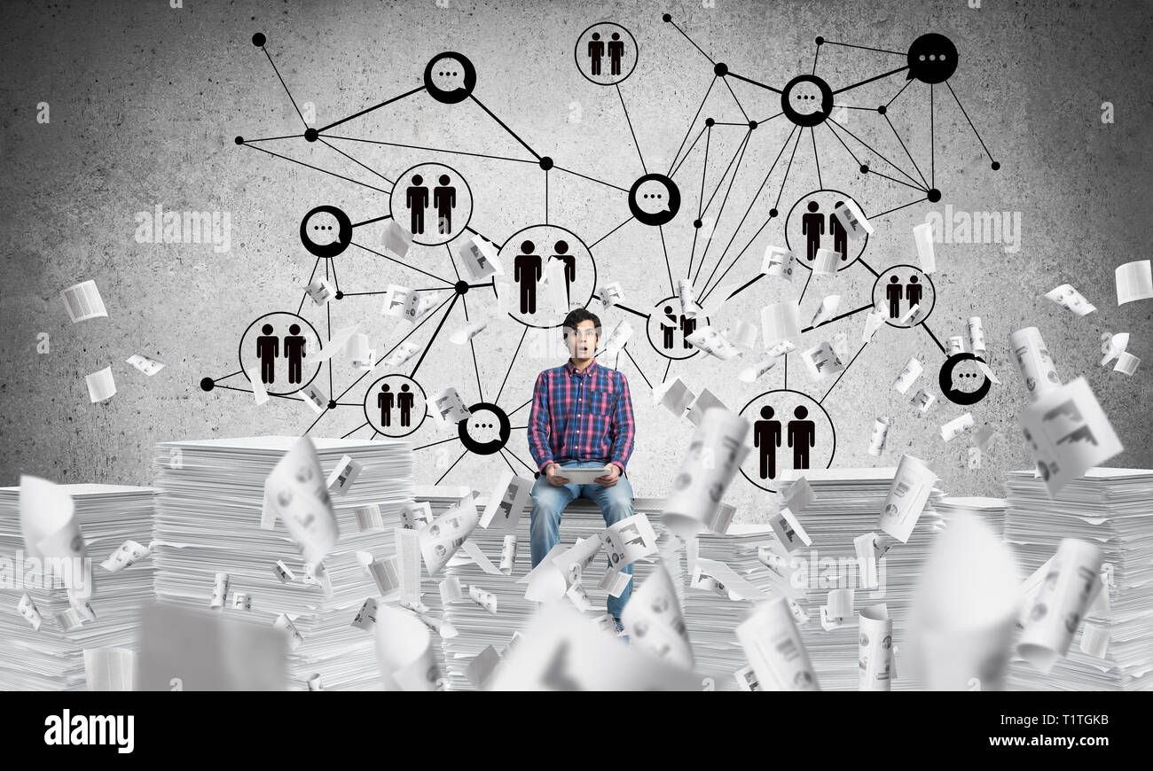 Attractive man sitting on pile of paper documents Stock Photo - Alamy