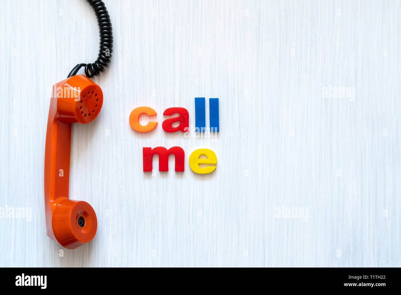 Phone handle hanging down on a cord near words Call me. Urgent business ...