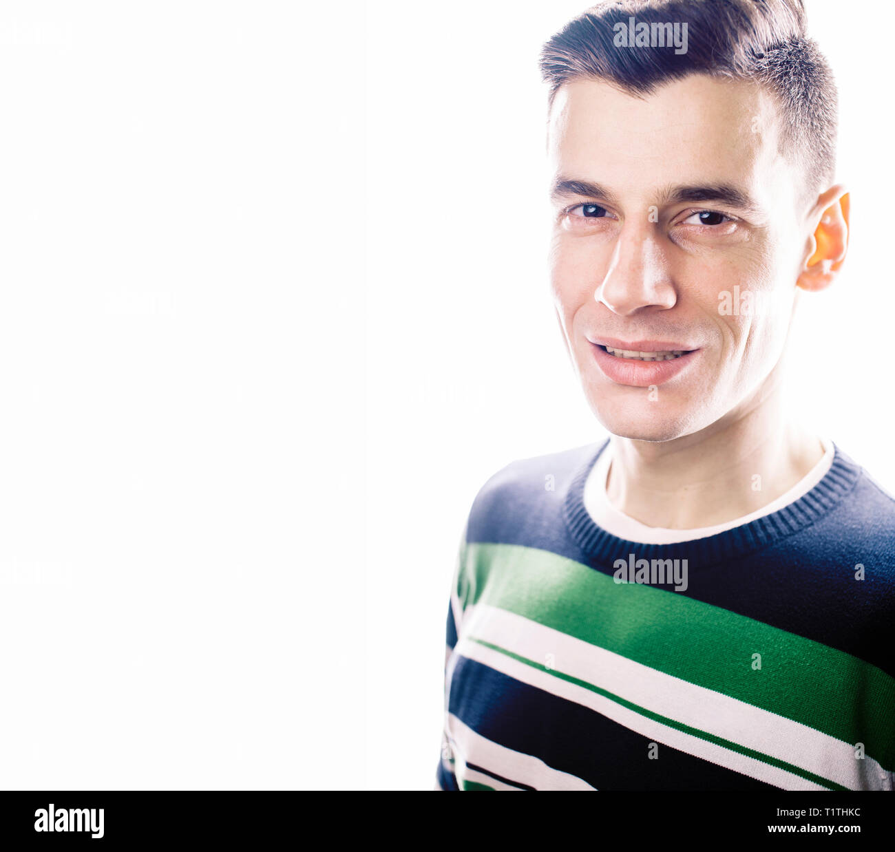 Portrait of a smart serious young man standing against white background ...
