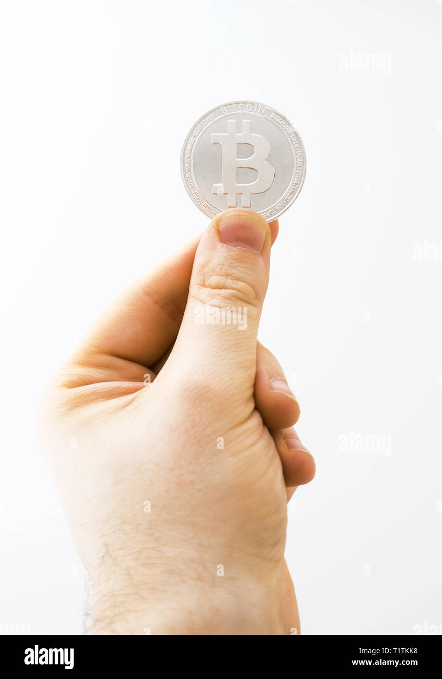 Man holding physical version of silver bitcoin on white background ...
