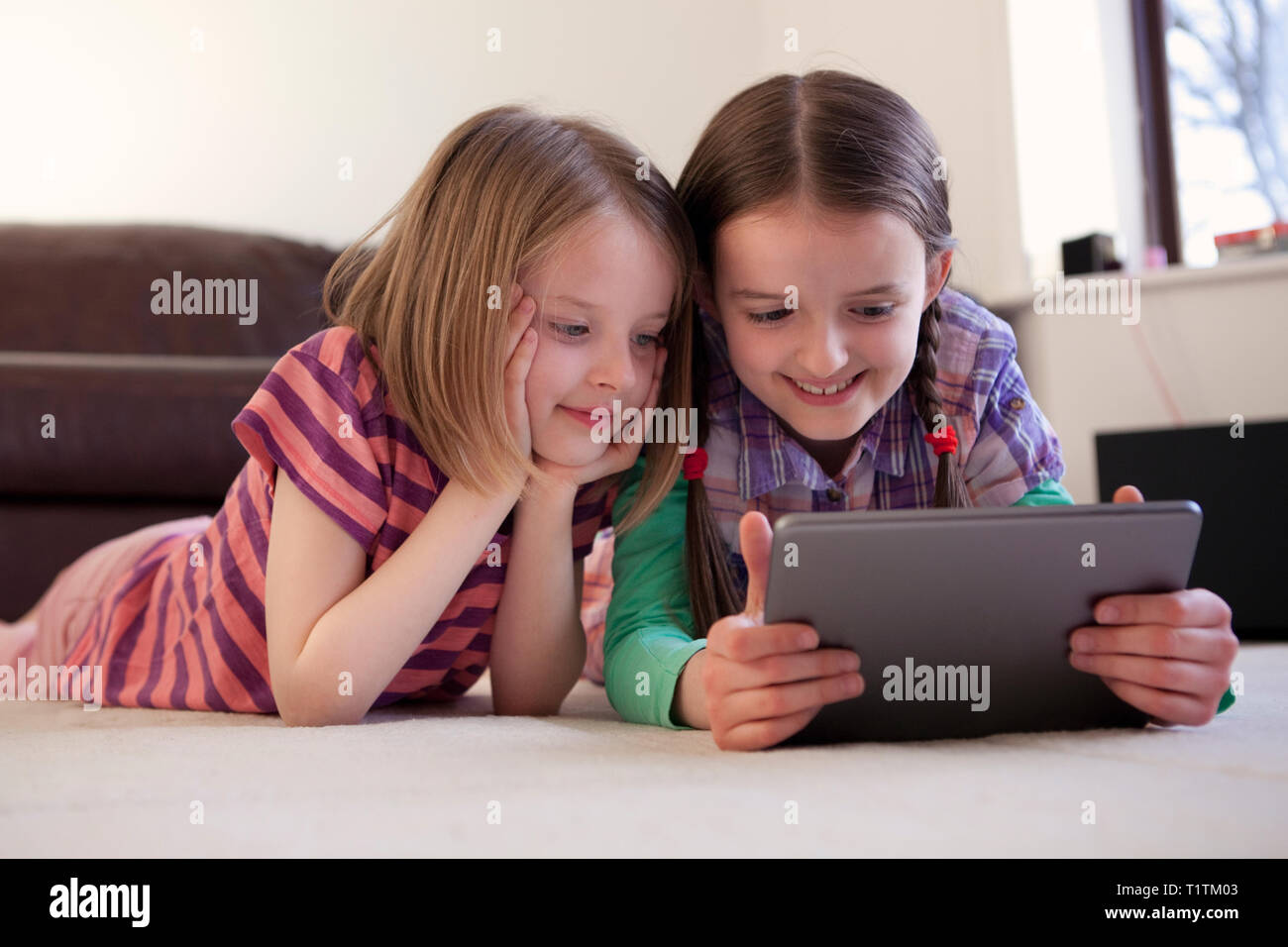 Two happy children using a tablet device together Stock Photo - Alamy