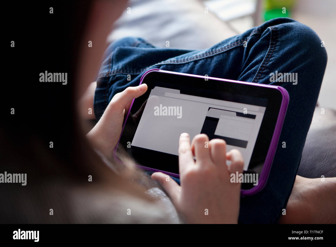 Over the shoulder view of girl using tablet device Stock Photo - Alamy