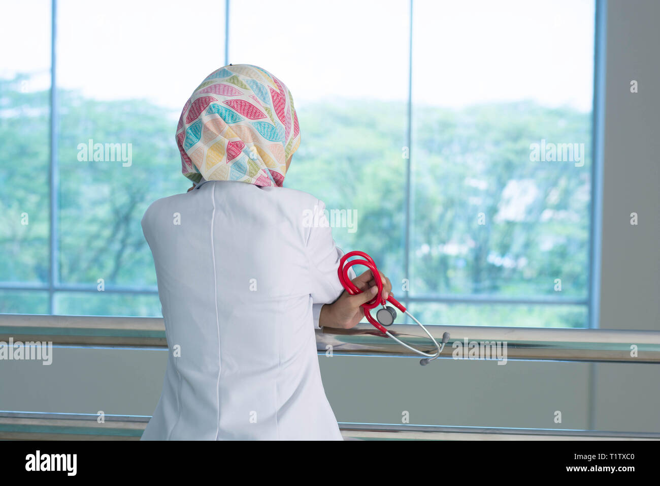 back of a female doctor facing the window's while thinking about ...