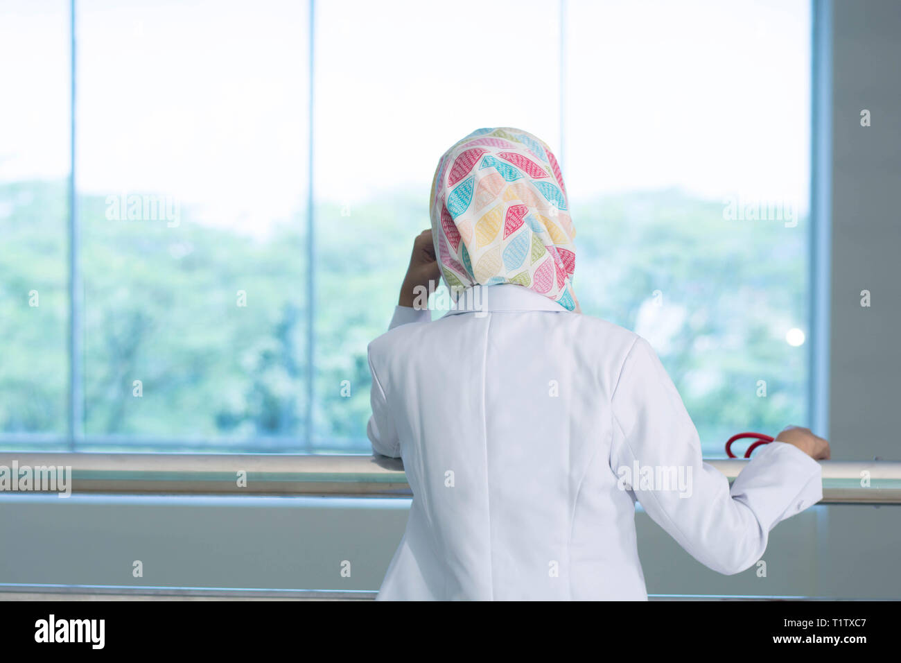 back of a female doctor facing the window's while thinking about ...