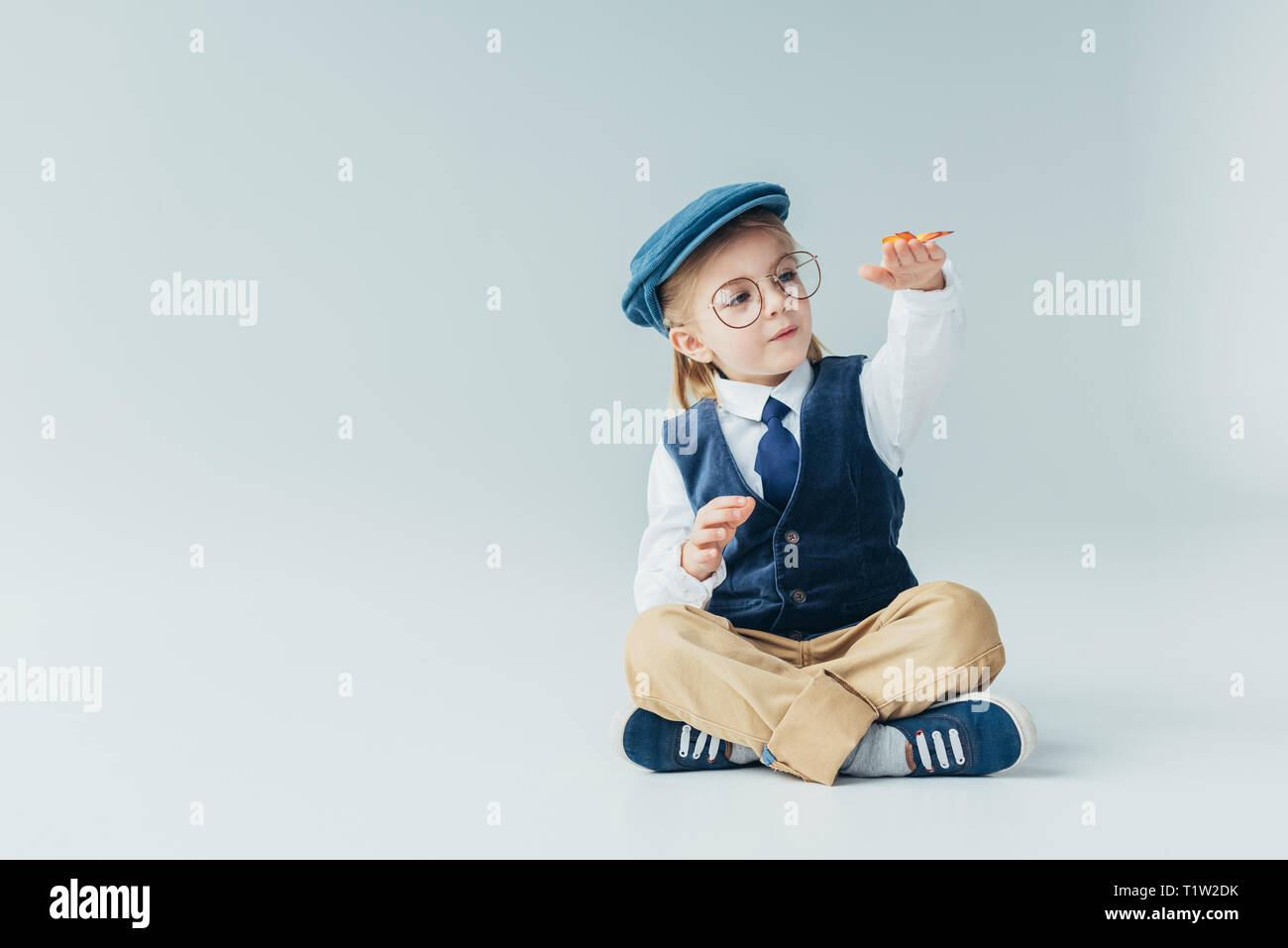 adorable kid sitting on floor with crossed legs and holding butterfly ...