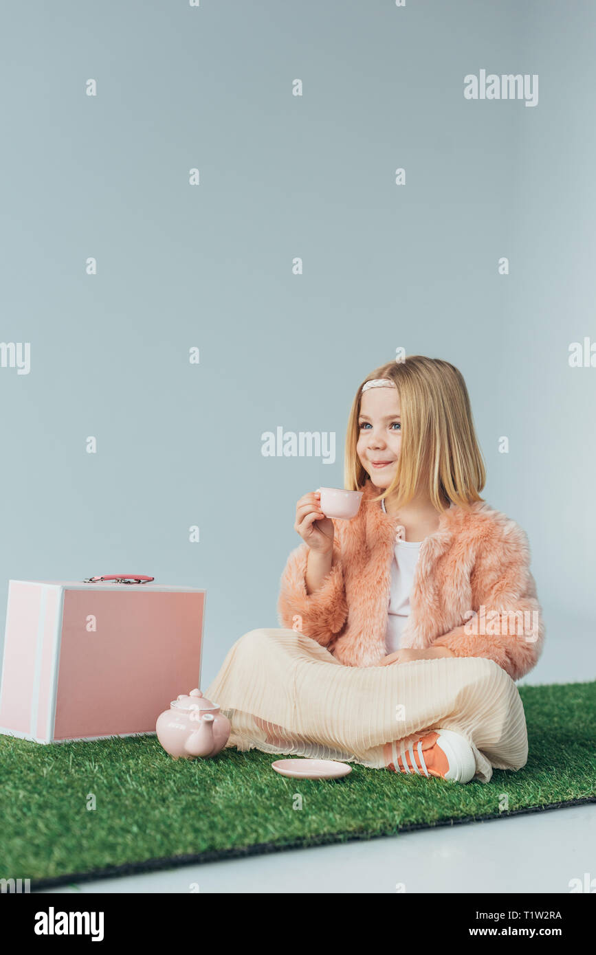 smiling child sitting with crossed legs playing with toy dishes and ...