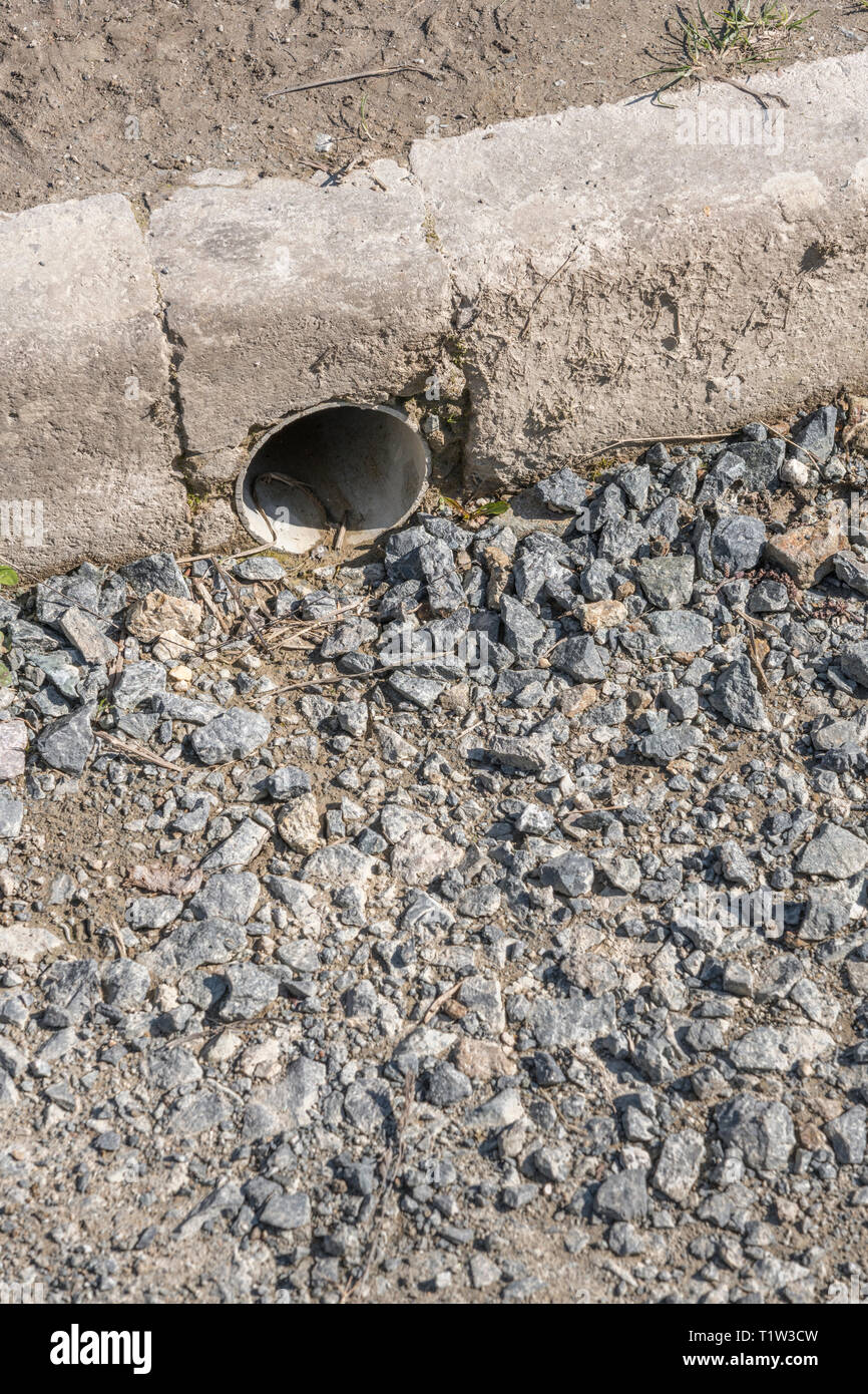 Small drainage pipe on side of country track. Metaphor for 'money down ...
