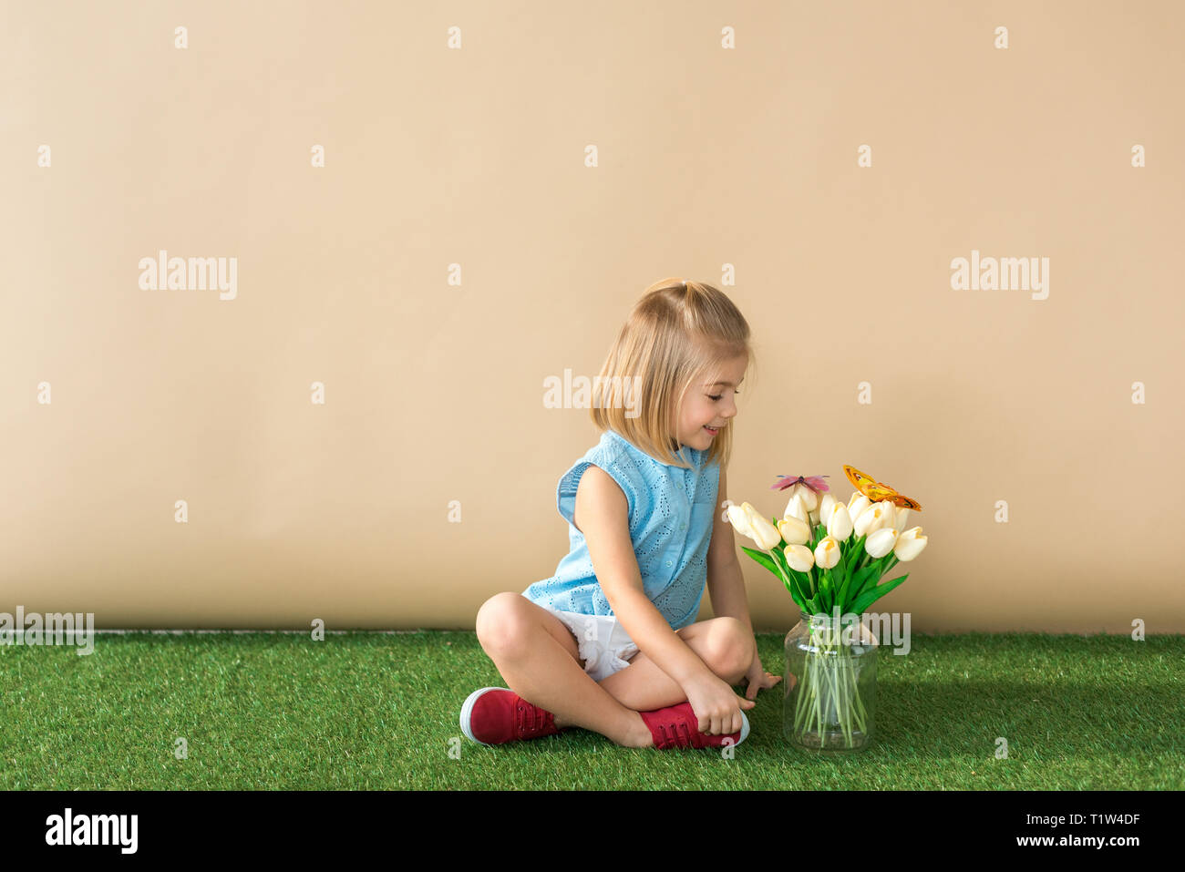 happy child sitting with crossed legs and looking at flowers and ...