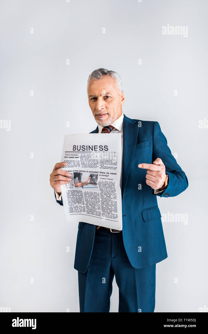 mature businessman pointing with finger at business newspaper isolated ...